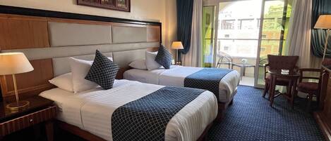 Quarto de hotel com duas camas, uma escrivaninha e uma cadeira.