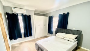 Quarto com cama, guarda-roupa e cortinas.
