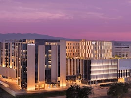 Um hotel moderno com um grande letreiro 'Mövenpick', fachada elegante com detalhes de iluminação vertical e um amplo saguão.