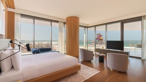 Quarto de hotel moderno com uma cama grande, televisão e varanda com vista para a praia e parque de diversões.