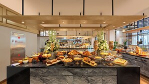 Buffet com diversos alimentos e um carretel de mangueira na parede.