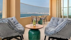Uma varanda com duas cadeiras, uma mesa e vista para o mar.