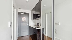 Uma cozinha moderna com painel de parede escuro, bancadas brancas e um exaustor de aço inoxidável.
