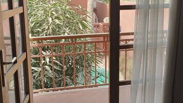Varanda aberta com vista para uma casa, uma palmeira e um chão de azulejos.