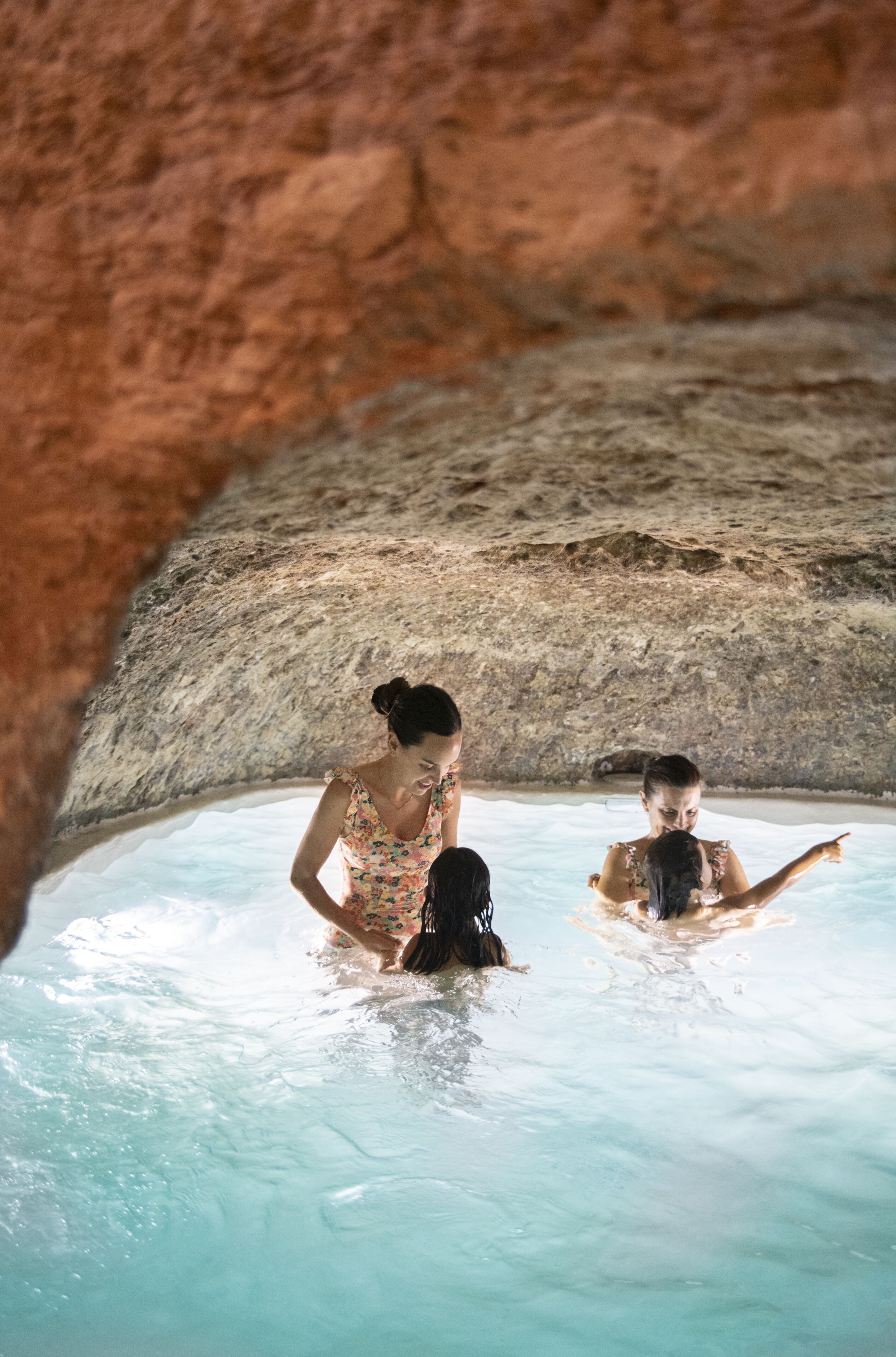 Uma nascente termal natural com três pessoas aproveitando a água.