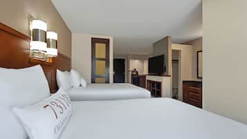 Quarto de hotel com duas camas, televisão, frigobar e banheiro.