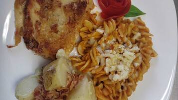 Um prato com escalope à milanesa, massa com queijo e batatas cozidas.