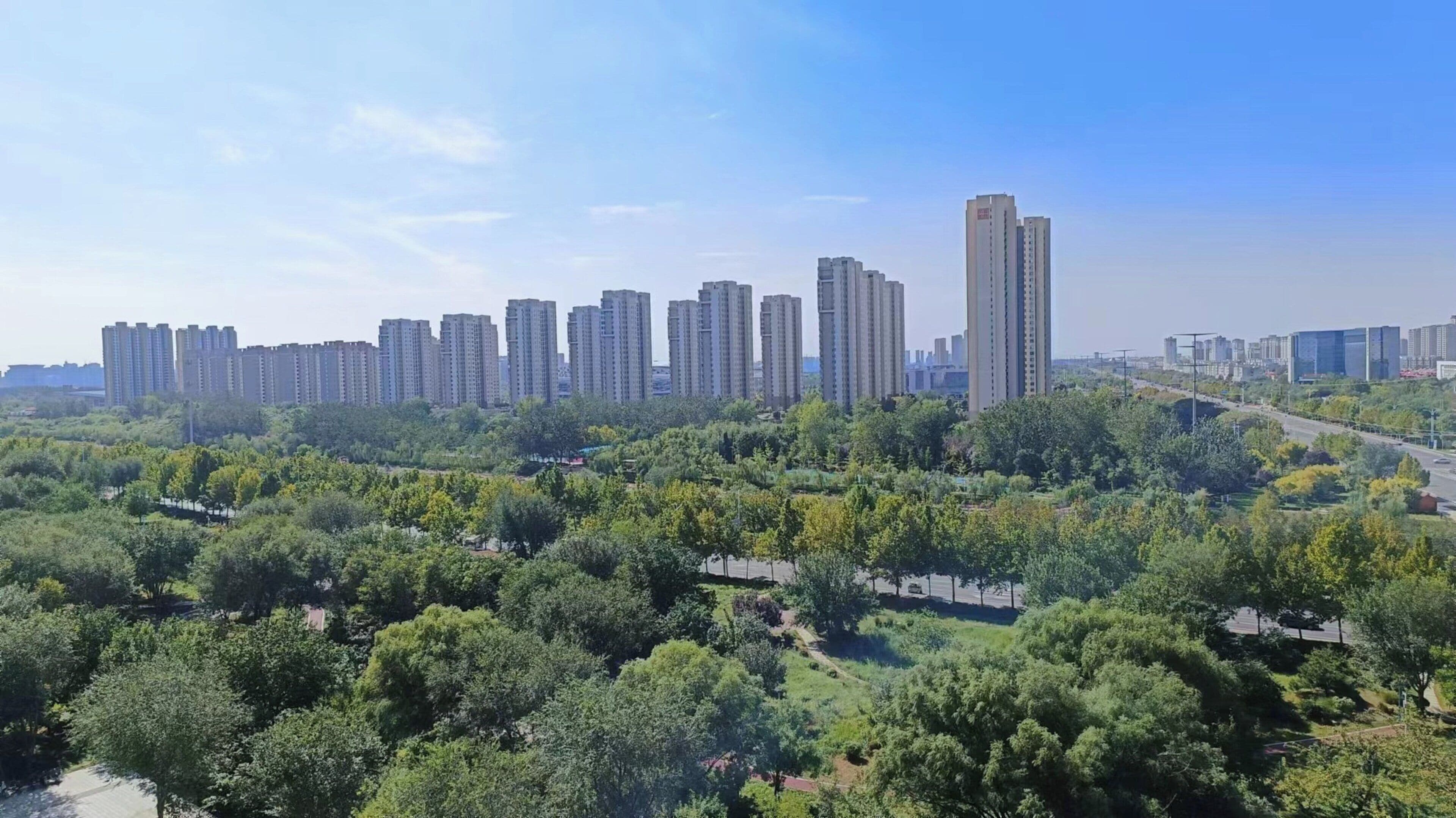 Uma área residencial com edifícios altos e um parque verdejante e extenso.
