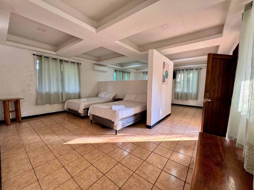 Quarto amplo com uma cama grande, um guarda-roupa de madeira e chão ladrilhado.