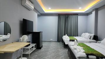 Quarto de hotel com duas camas, uma escrivaninha, um espelho, uma televisão e um aparelho de ar condicionado.