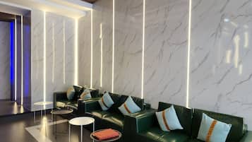 Um hall moderno com um conjunto de sofá verde, paredes de mármore branco e um design de teto elegante.