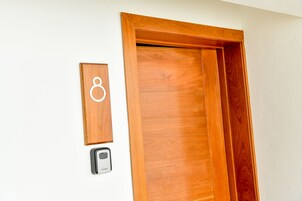 Uma porta de madeira com uma placa de número e um videotelefone.