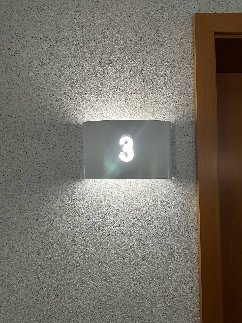 Luminária fixa na parede com o número '3' iluminado.