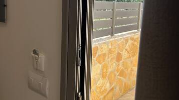 Visão através de uma porta, com uma parede de pedra e cerca de madeira no exterior.