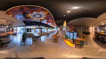 Um restaurante espaçoso com decoração moderna, apresentando um bar central, diversas opções de assentos e um teto decorativo.