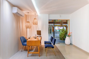 Uma sala de jantar moderna com mesa de madeira, cadeiras azuis e luminárias pendentes.