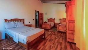 Quarto com cama de madeira, duas mesas de cabeceira, um guarda-roupa e uma porta que dá para outro cômodo.
