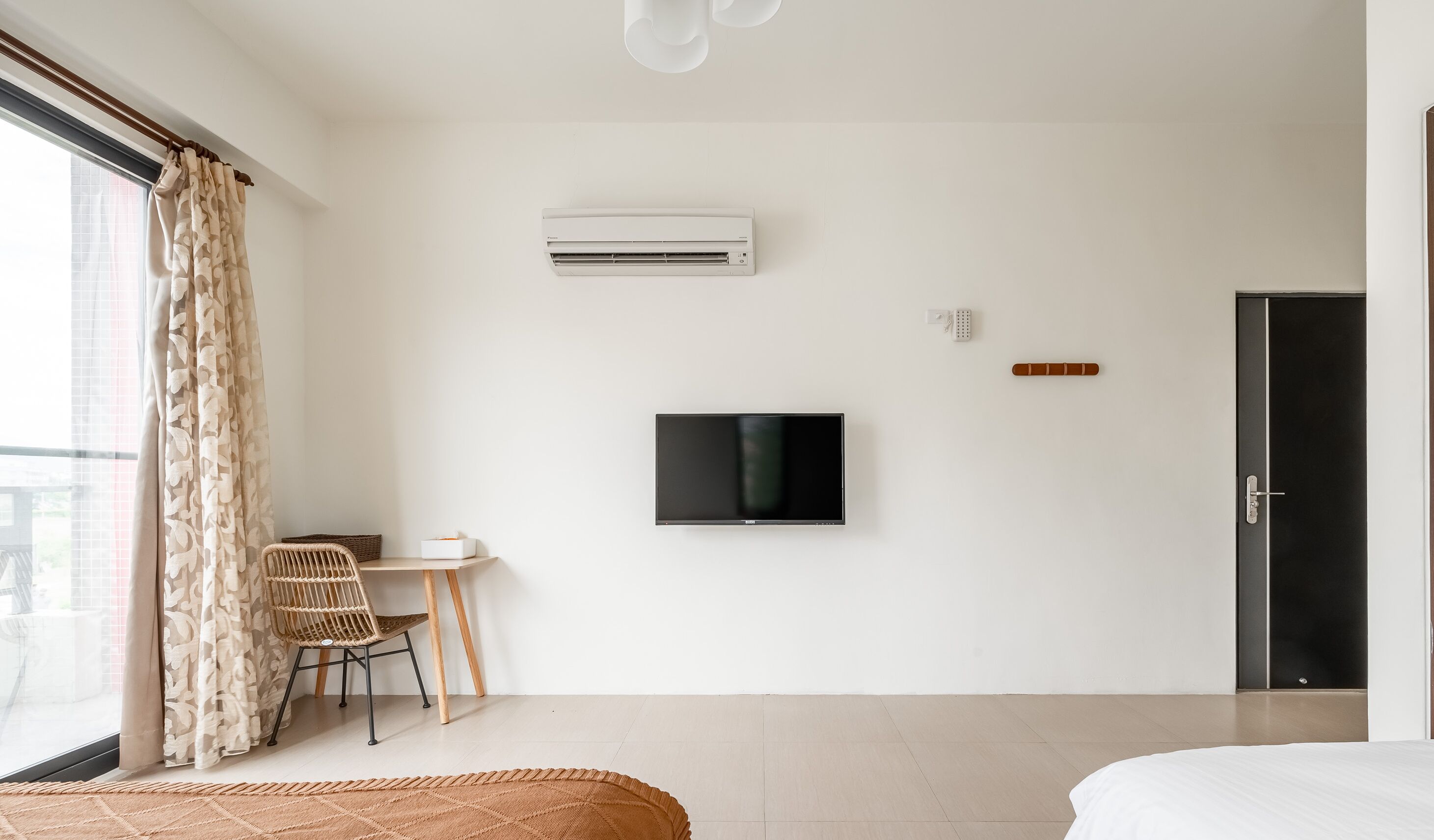 Quarto de hotel moderno com televisão de tela plana, ar condicionado e uma porta.