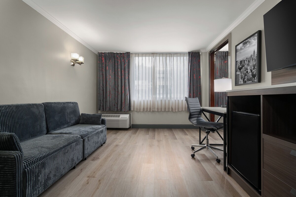 Quarto moderno com sofá, escrivaninha e cadeira.