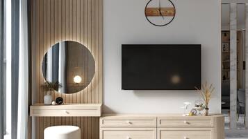 Uma casa de banho moderna com toucador de madeira, espelho redondo, televisão na parede e design minimalista.