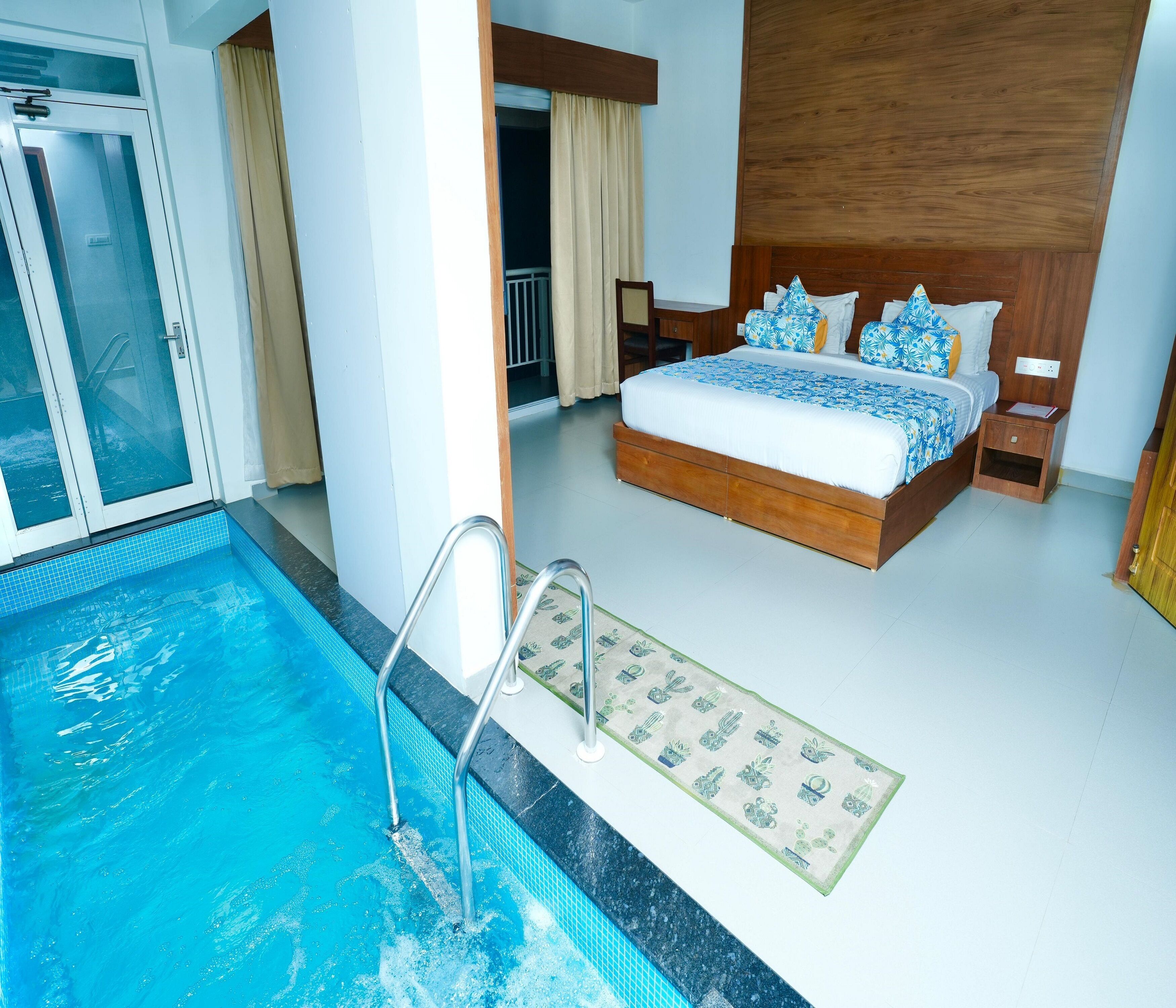 Quarto de hotel com piscina, cama de madeira e mesa de cabeceira.