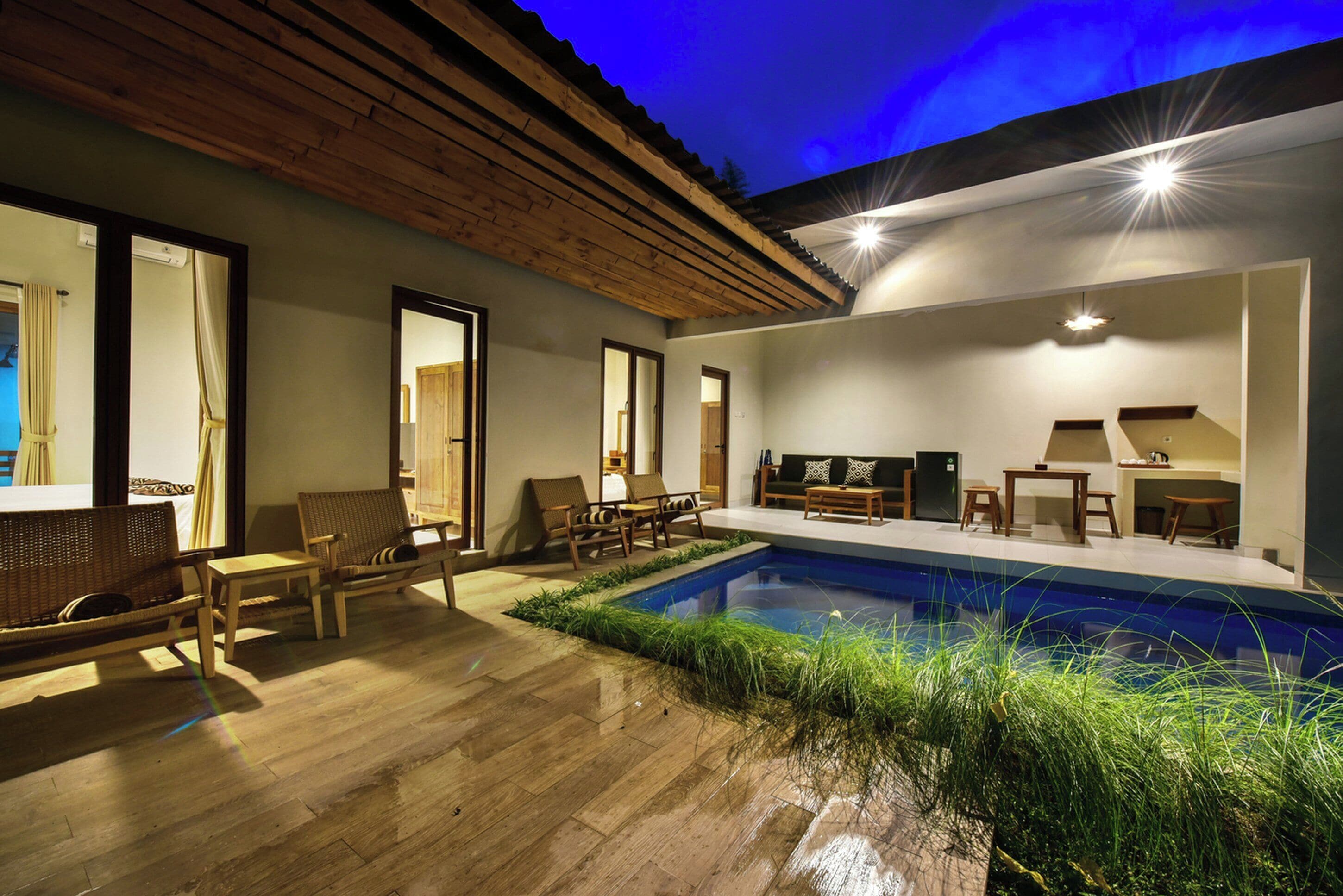 Uma área externa moderna com piscina, móveis de madeira e um alpendre coberto.