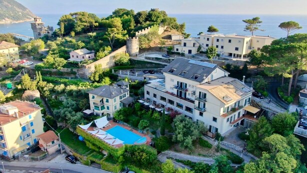 Uma área residencial costeira com casas modernas, uma piscina e uma estrutura semelhante a um castelo.