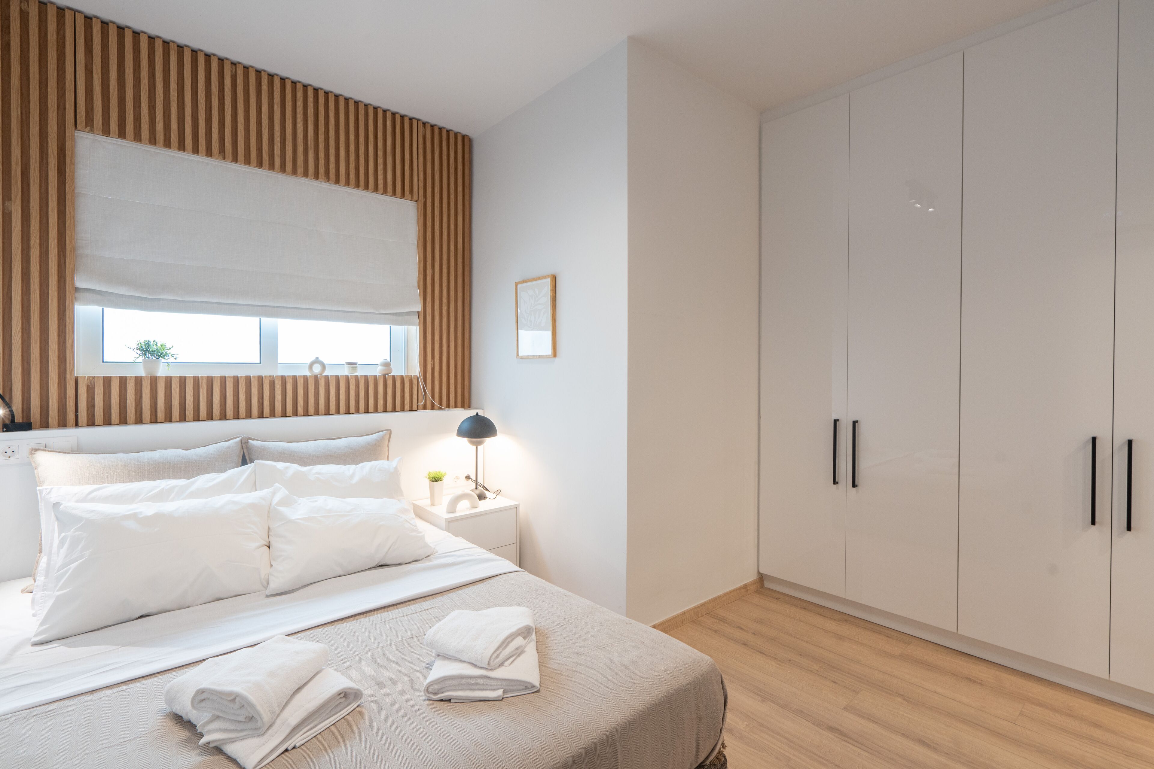 Quarto moderno com cama, mesa de cabeceira, abajur e guarda-roupa.