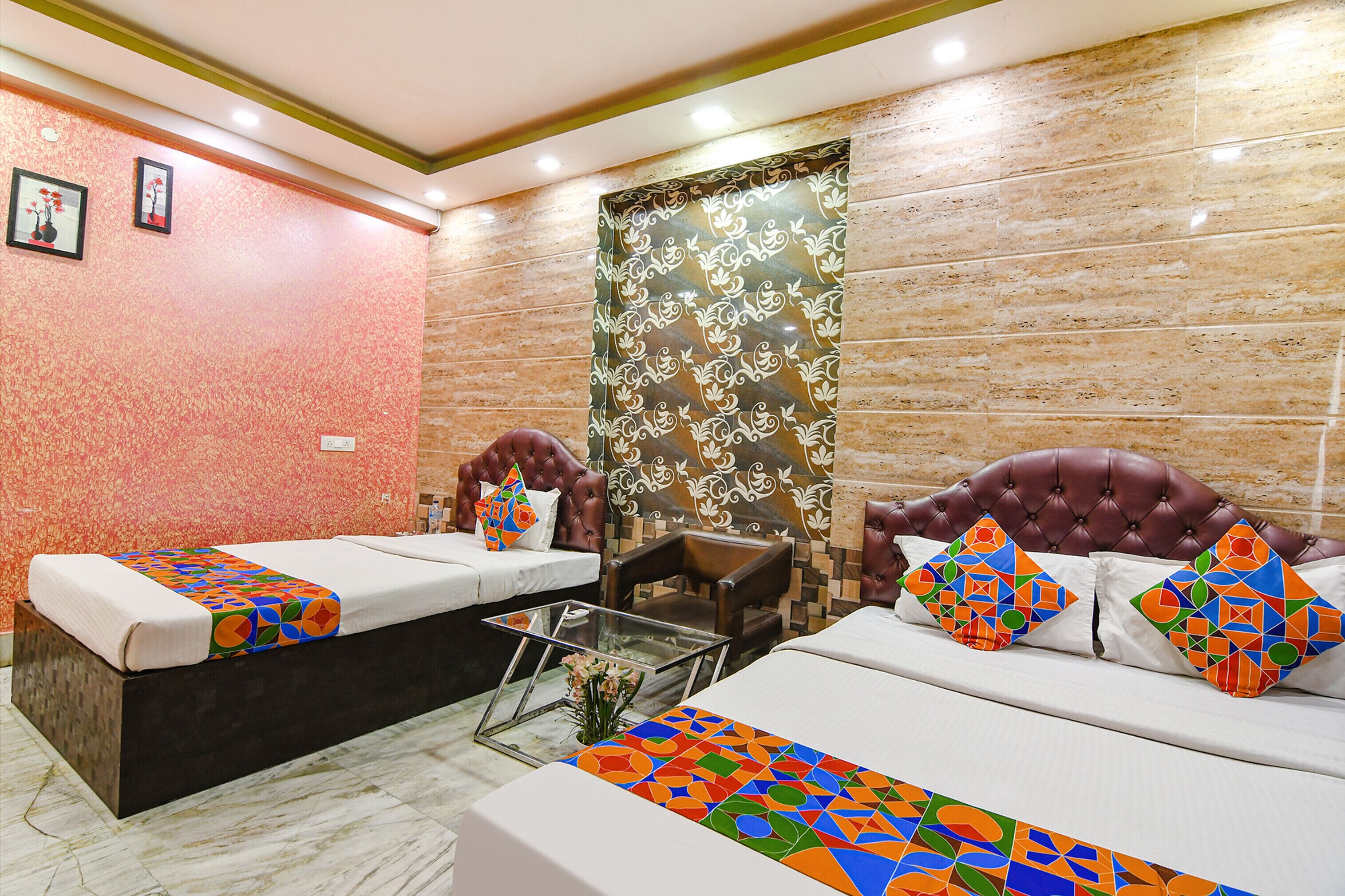 Quarto de hotel com duas camas, um espaço para sentar e um detalhe decorativo na parede.
