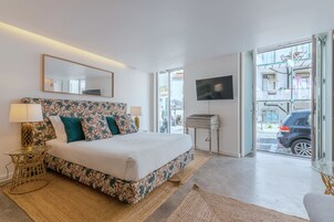 Quarto com cama, televisão, janela e vista para a rua.