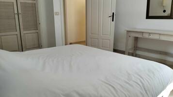 Quarto com uma cama grande, mesa de cabeceira e guarda-roupa.