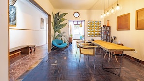 Um interior moderno com uma mesa de madeira comprida, cadeiras azuis e luminárias pendentes.