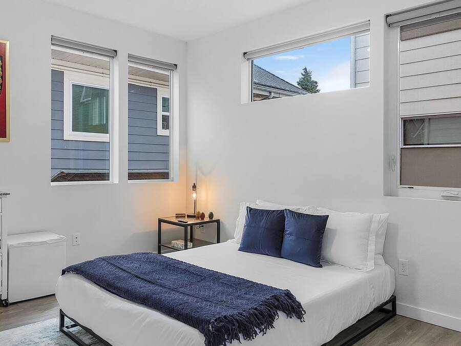 Quarto com cama, mesa de cabeceira com abajur e janela.