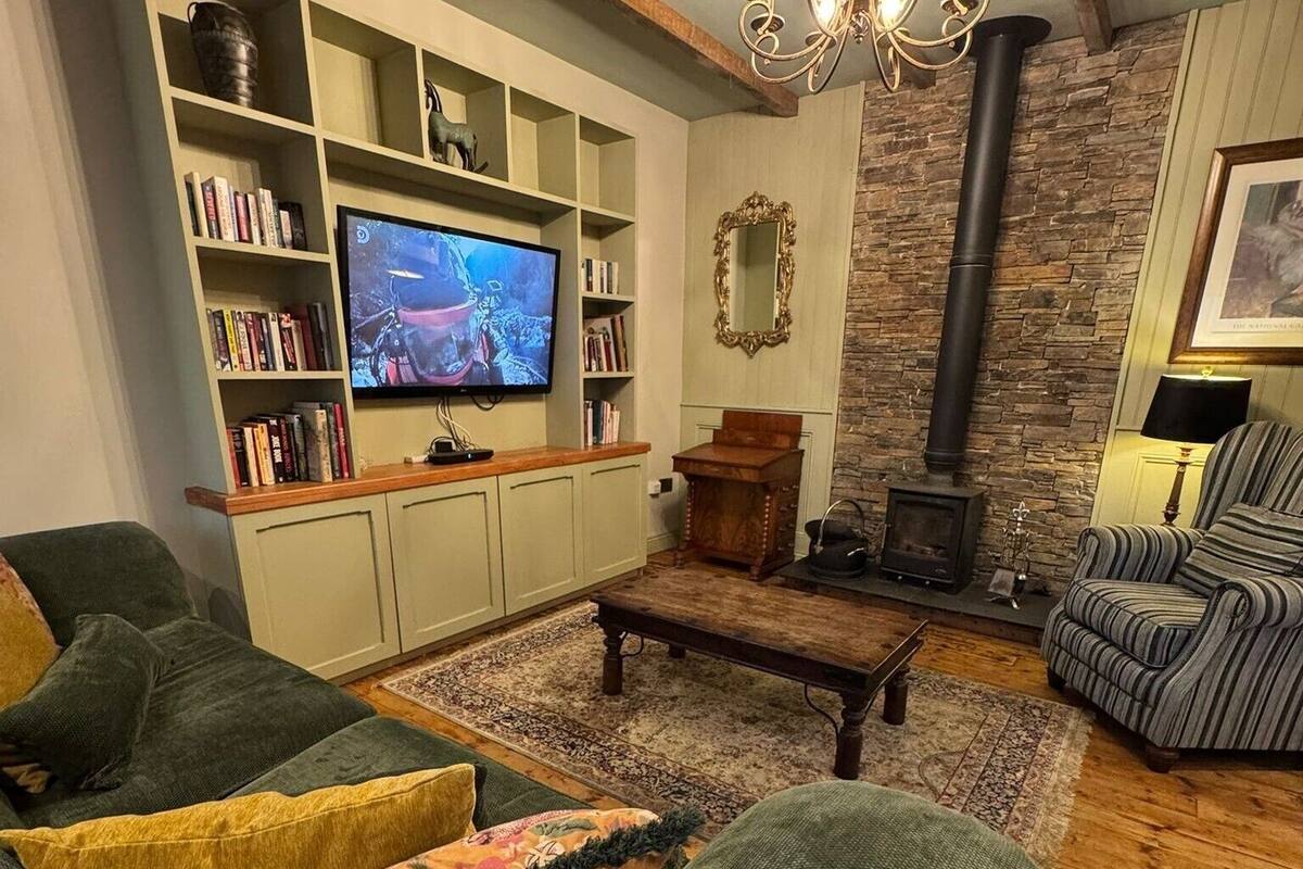 Uma sala de estar aconchegante com televisão, estantes de livros, lareira e assentos confortáveis.