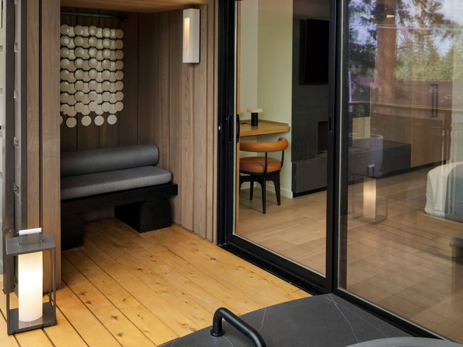 Uma área de spa moderna com hidromassagem, piso de madeira, espaço para sentar e porta de vidro que dá para uma área externa.