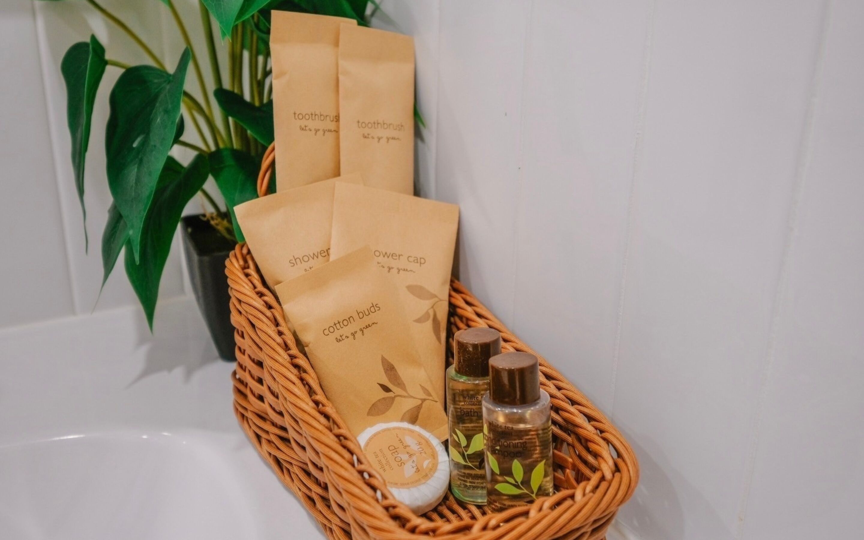 Uma cesta de vime com produtos de higiene, incluindo sabonete, cotonetes e frascos de shampoo e condicionador.