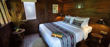 Quarto de cabana de madeira com uma cama, uma mesa pequena com frutas e um abajur.
