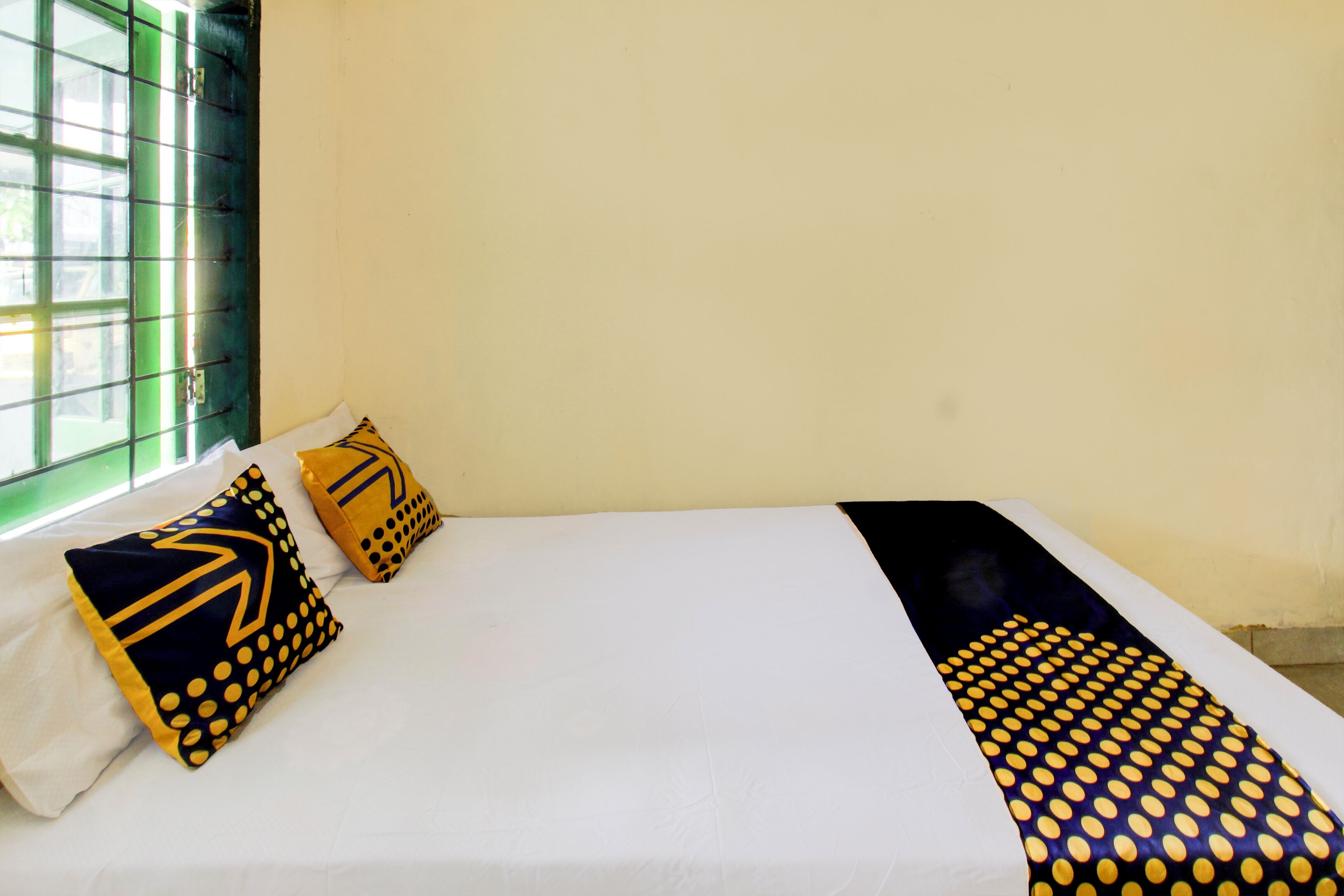 Quarto de hotel com cama, almofadas e janela.
