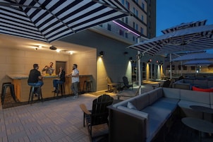 Uma área de bar ao ar livre com guarda-sóis listrados, assentos e balcão.
