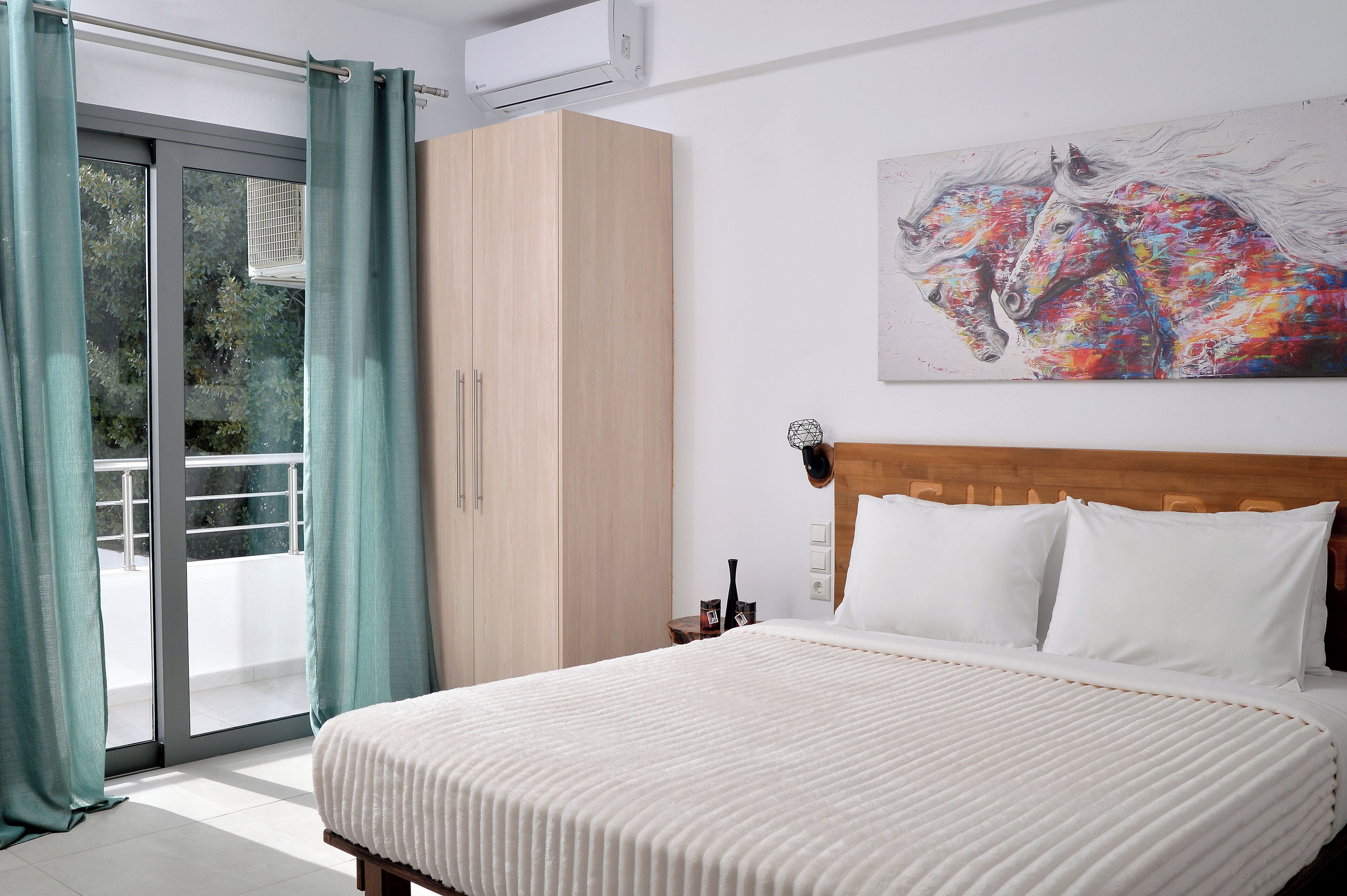Quarto com cama, guarda-roupa, um quadro e vista através de uma porta de vidro.