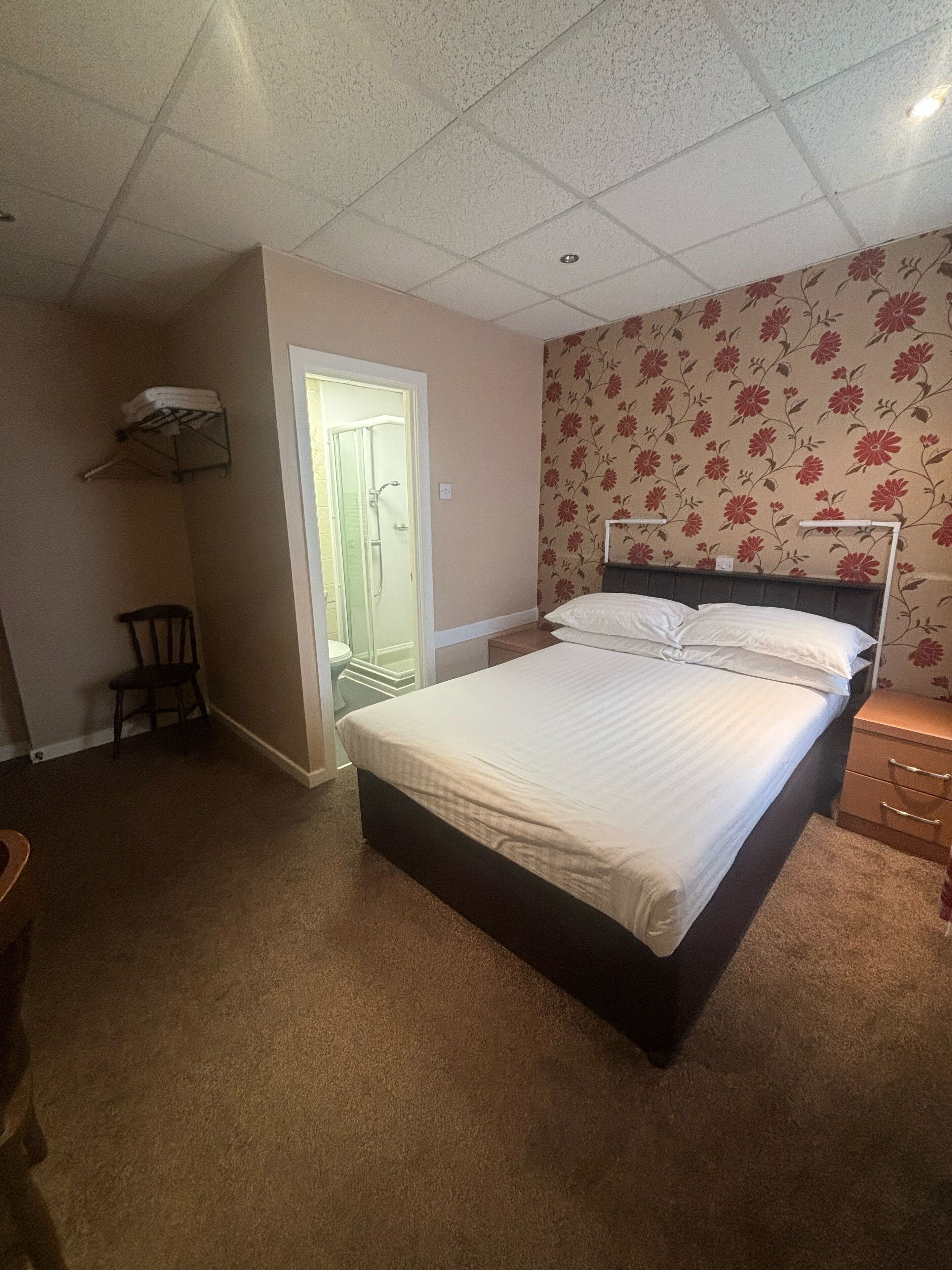 Quarto com cama, cadeira, mesa de cabeceira e porta para um banheiro.