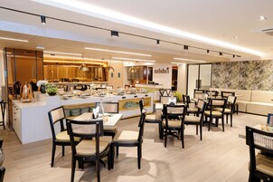 Um restaurante moderno com ilha central, várias mesas e cadeiras.