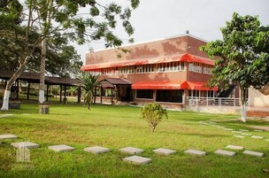 Um edifício com toldo vermelho, rodeado por um espaço gramado com pedras e árvores.