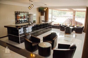 Uma área de estar moderna com bar, assentos de couro e vista para o exterior.