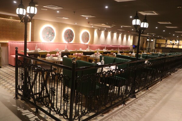 Um restaurante com cabines e mesas, piso estampado e iluminação decorativa.