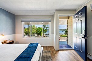 Quarto de hotel com cama, janela com vista para um lago e porta que dá para uma varanda.