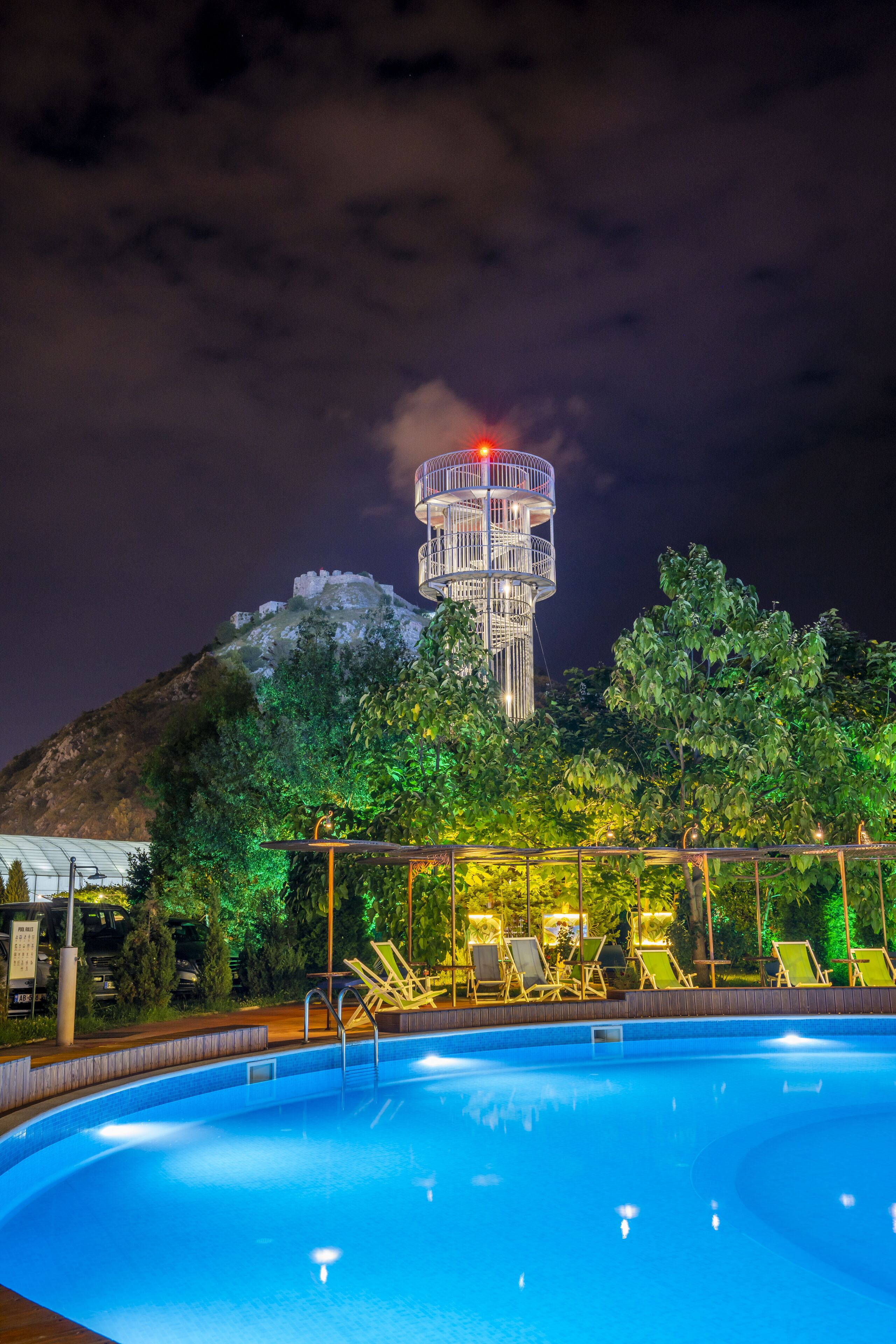 Uma piscina com espreguiçadeiras e um tanque d'água ao fundo.