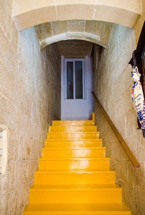 Uma escadaria com degraus amarelos que leva a uma porta no topo.