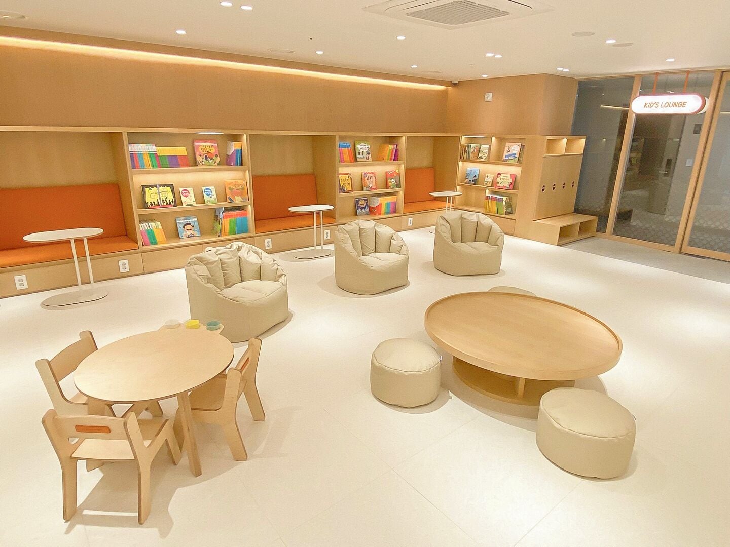 Uma sala de recreação infantil com áreas de estar, mesas e estantes.