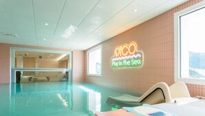 Piscina interna com um letreiro de neon que diz "Pico Play in the Sea" e vista da área da piscina.